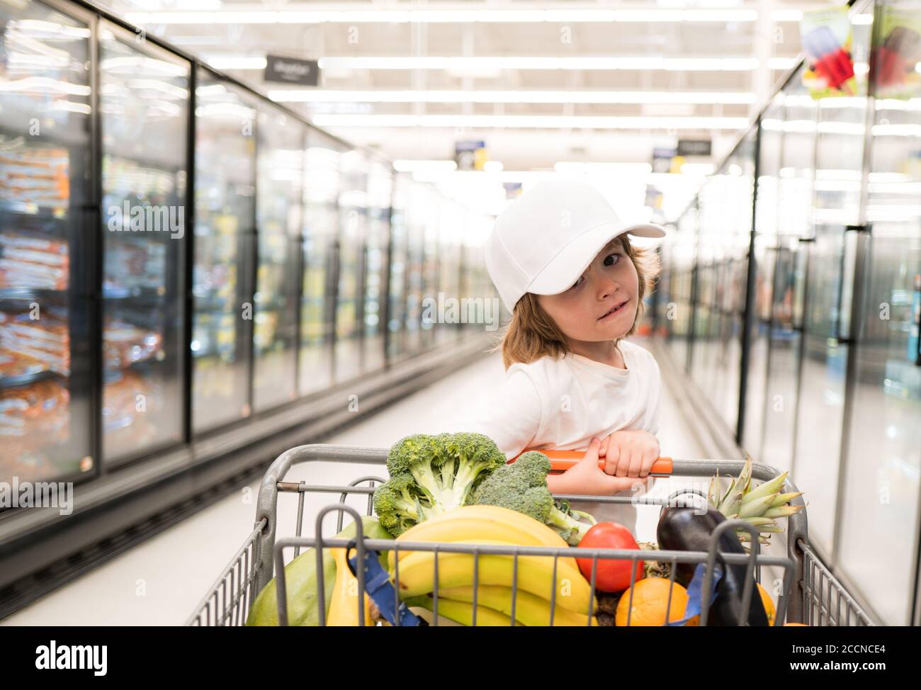 Funny shopping. Joyful beautiful child boy in supermarket buys ...