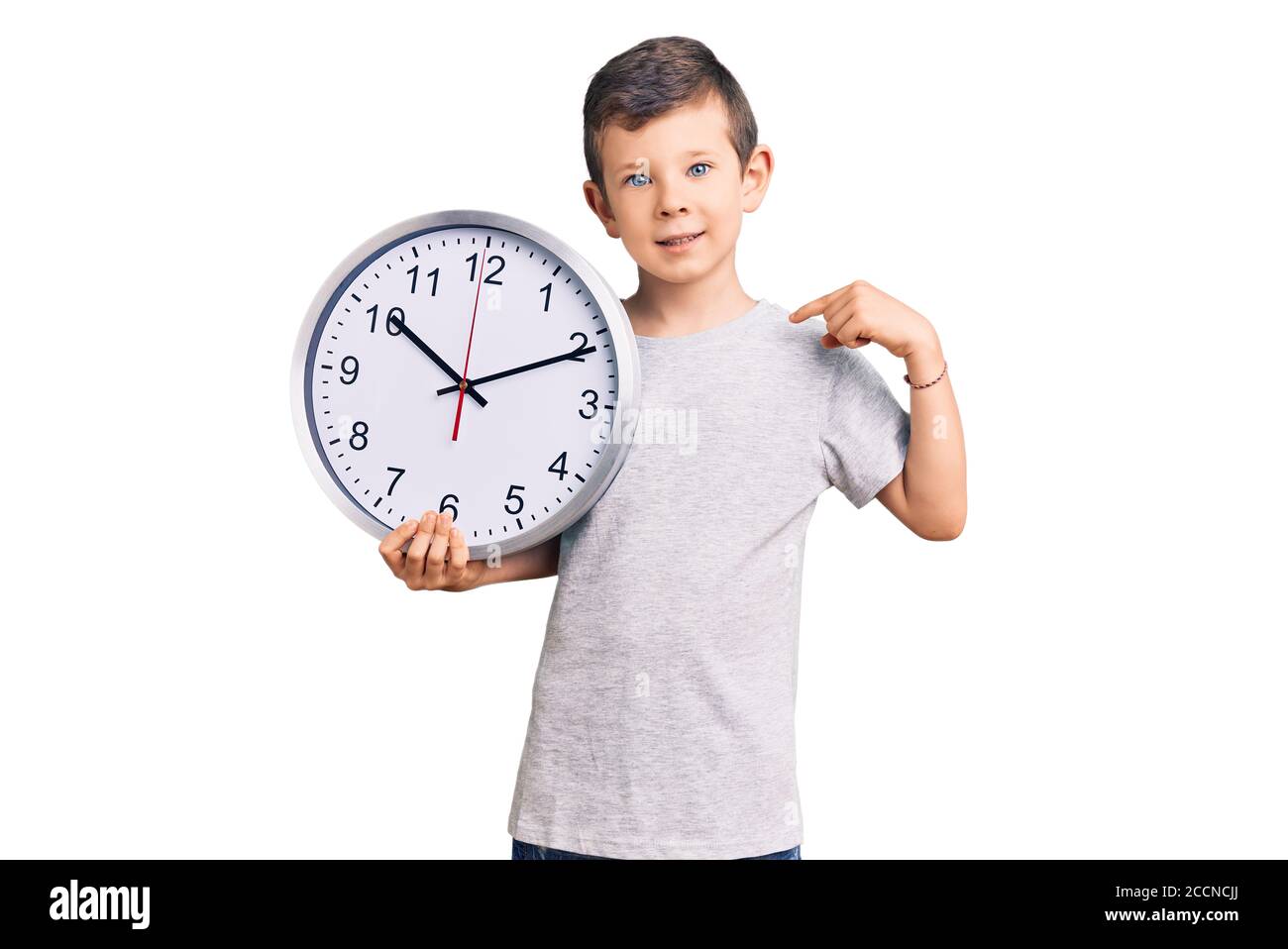 Cute blond kid holding big clock pointing finger to one self smiling ...