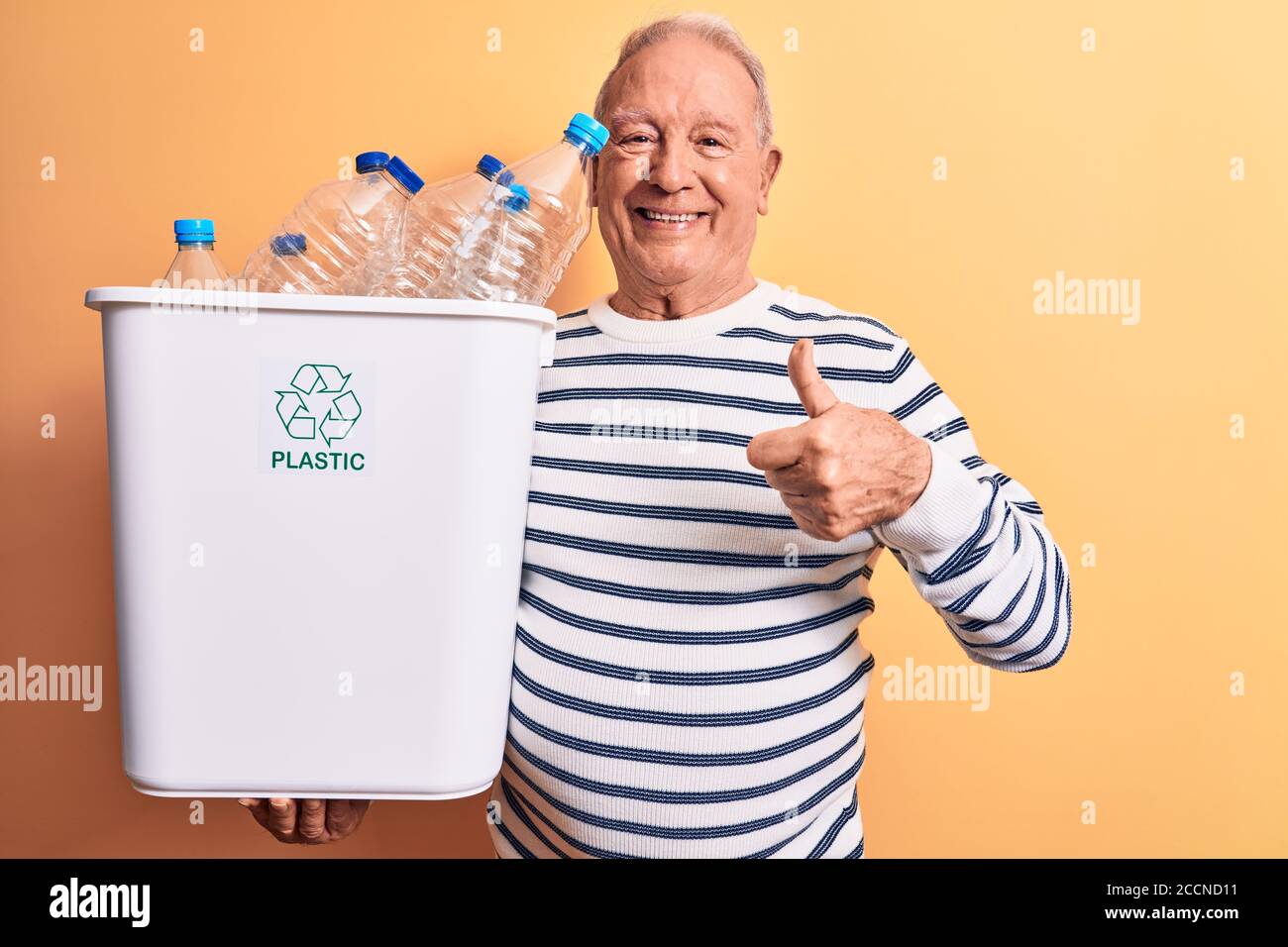 Senior handsome grey-haired man recycling holding wastebasket full of ...