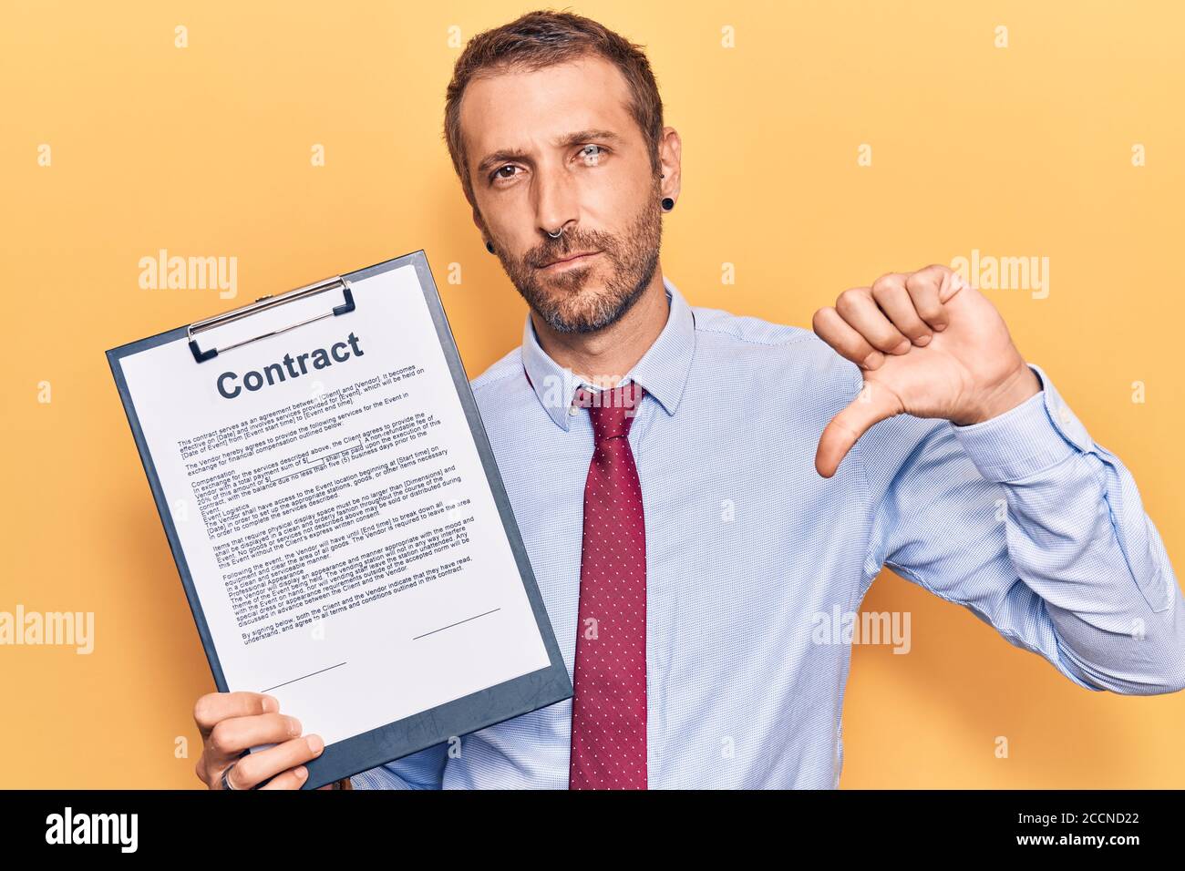 Young handsome man holding clipboard with contract document with angry ...