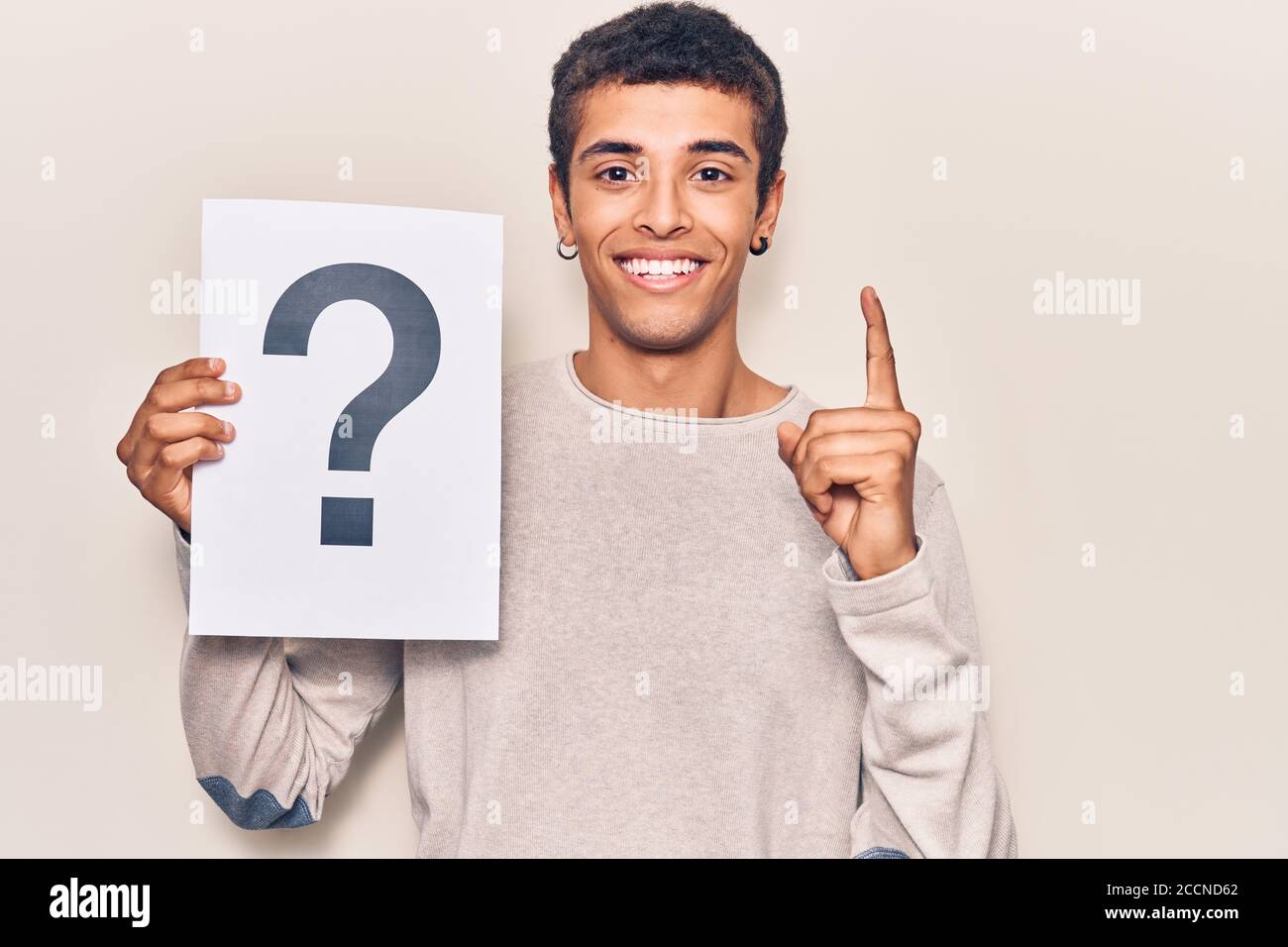 Young african amercian man holding question mark smiling with an idea ...