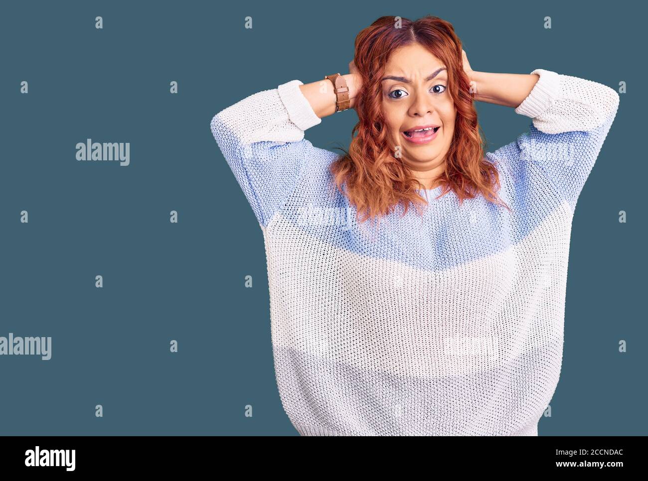 Young latin woman wearing casual clothes crazy and scared with hands on ...
