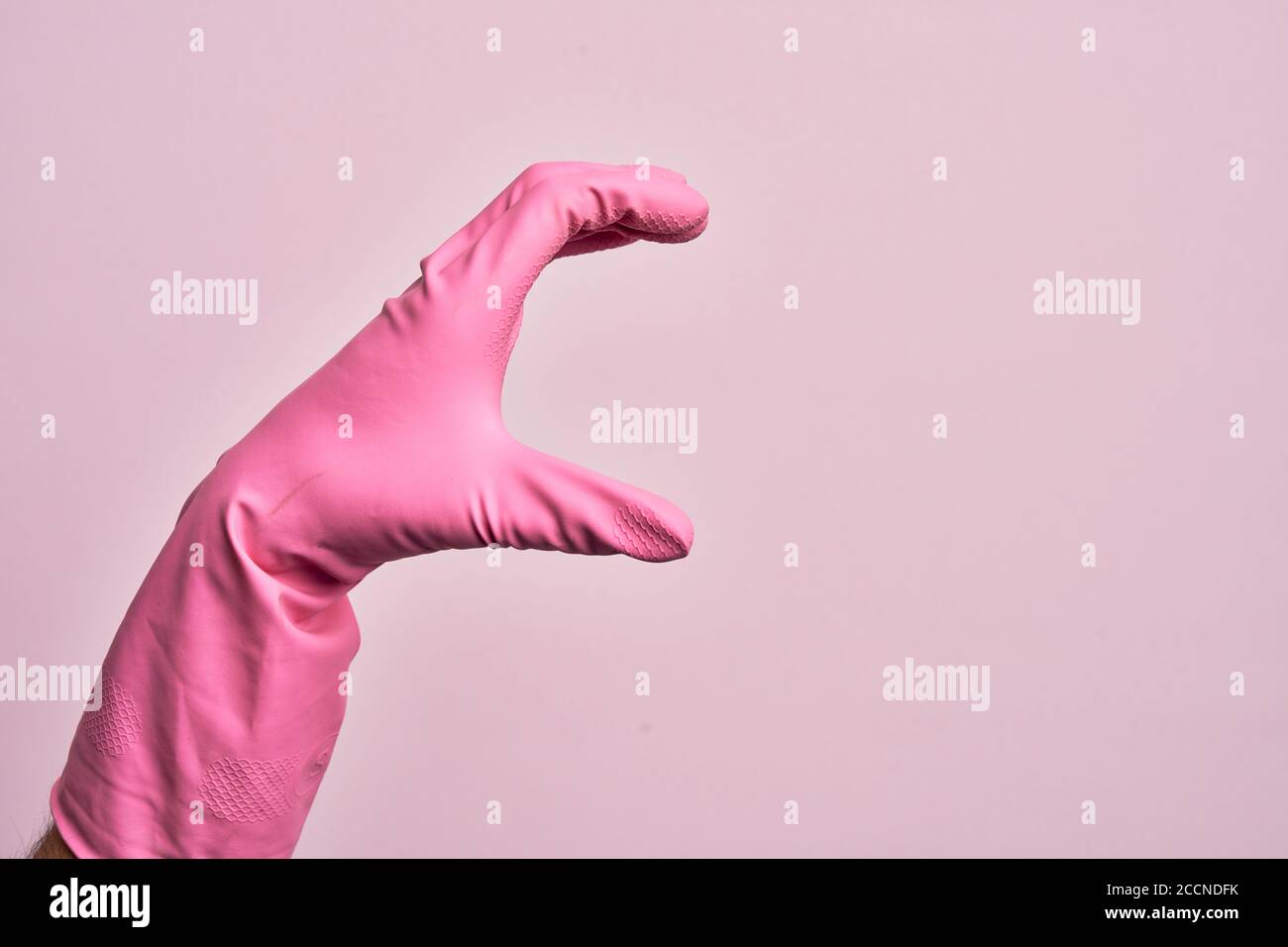 Hand of caucasian young man with cleaning glove over isolated pink ...