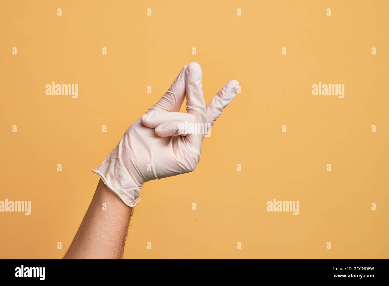 Hand of caucasian young man with medical glove over isolated yellow ...