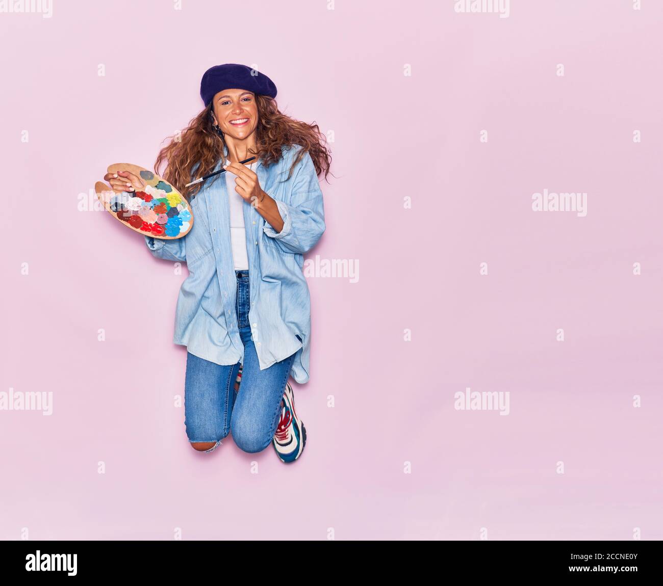 Young beautiful curly artist woman with tattoo wearing french beret ...