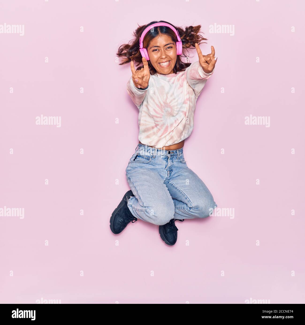 Young beautiful latin woman listening to music using headphones smiling ...