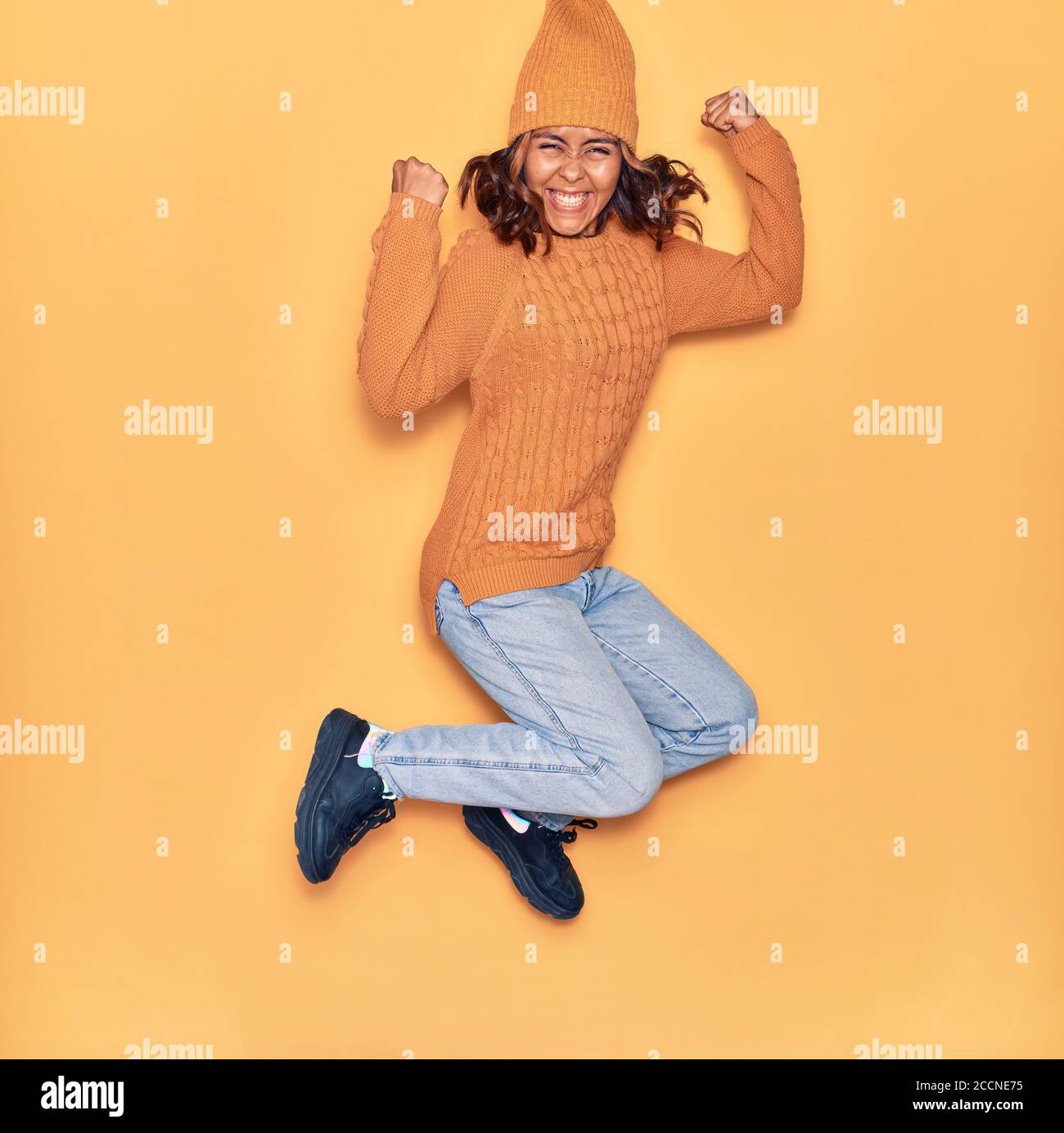 Young beautiful latin woman wearing wool cap and sweater smiling happy ...