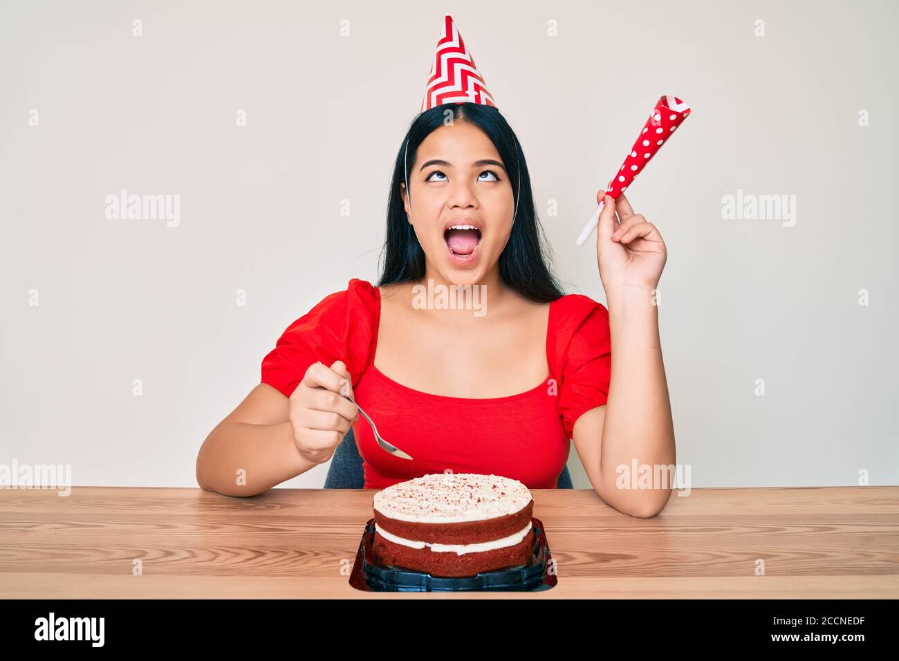 Young asian girl celebrating birthday with cake angry and mad screaming ...