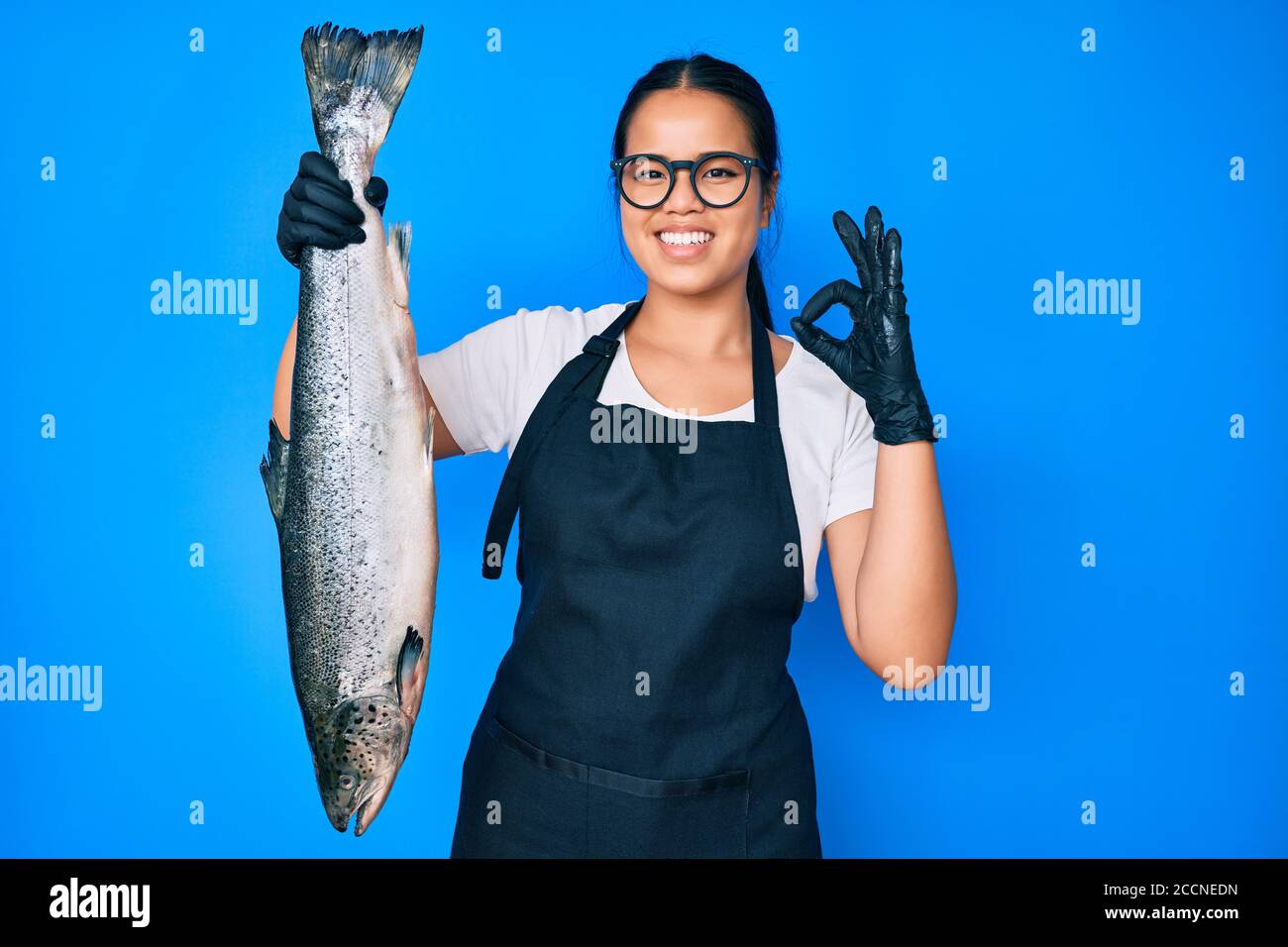 Young beautiful asian girl fishmonger selling fresh raw salmon doing ok ...
