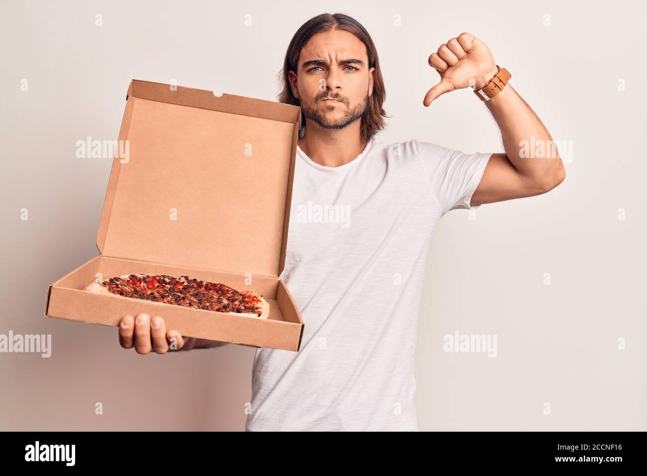 Young handsome man holding delivery pizza box with angry face, negative ...