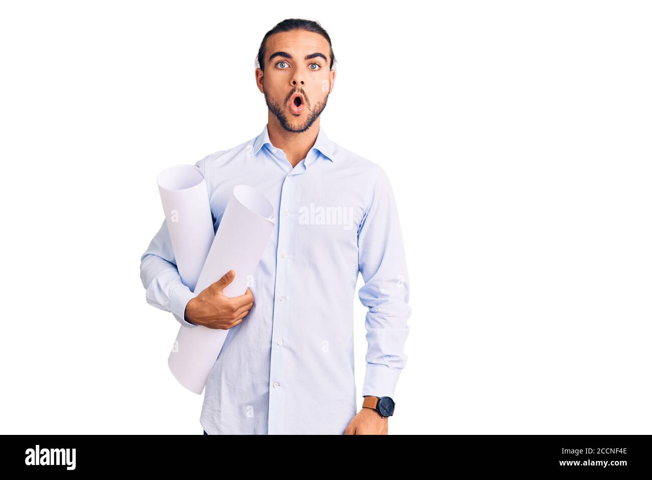 Young handsome man holding paper blueprints scared and amazed with open ...