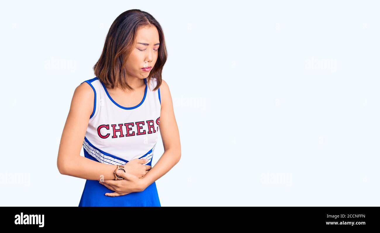 Young beautiful chinese girl wearing cheerleader uniform with hand on ...