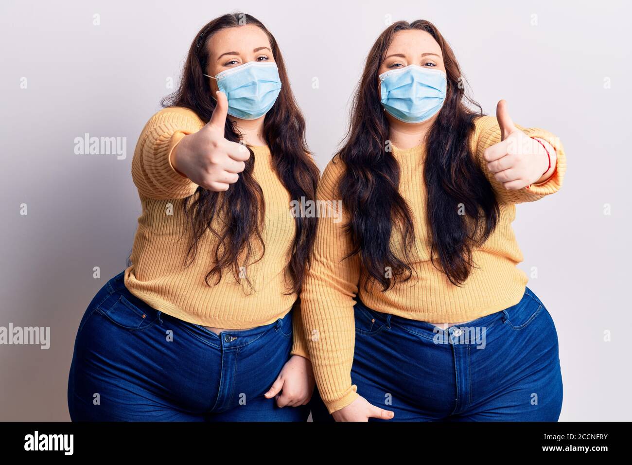 Young plus size twins wearing medical mask approving doing positive ...