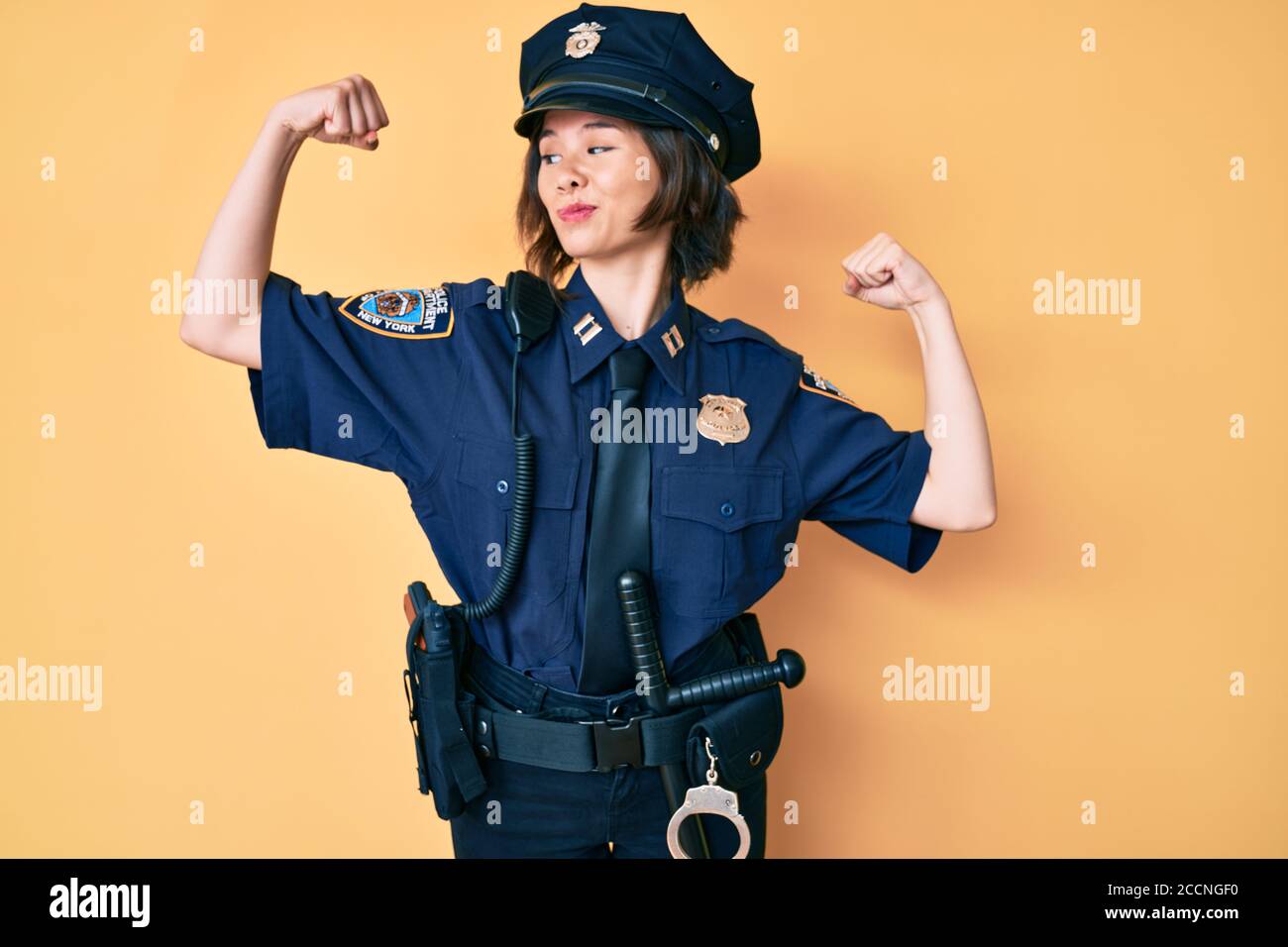 Young beautiful woman wearing police uniform showing arms muscles ...