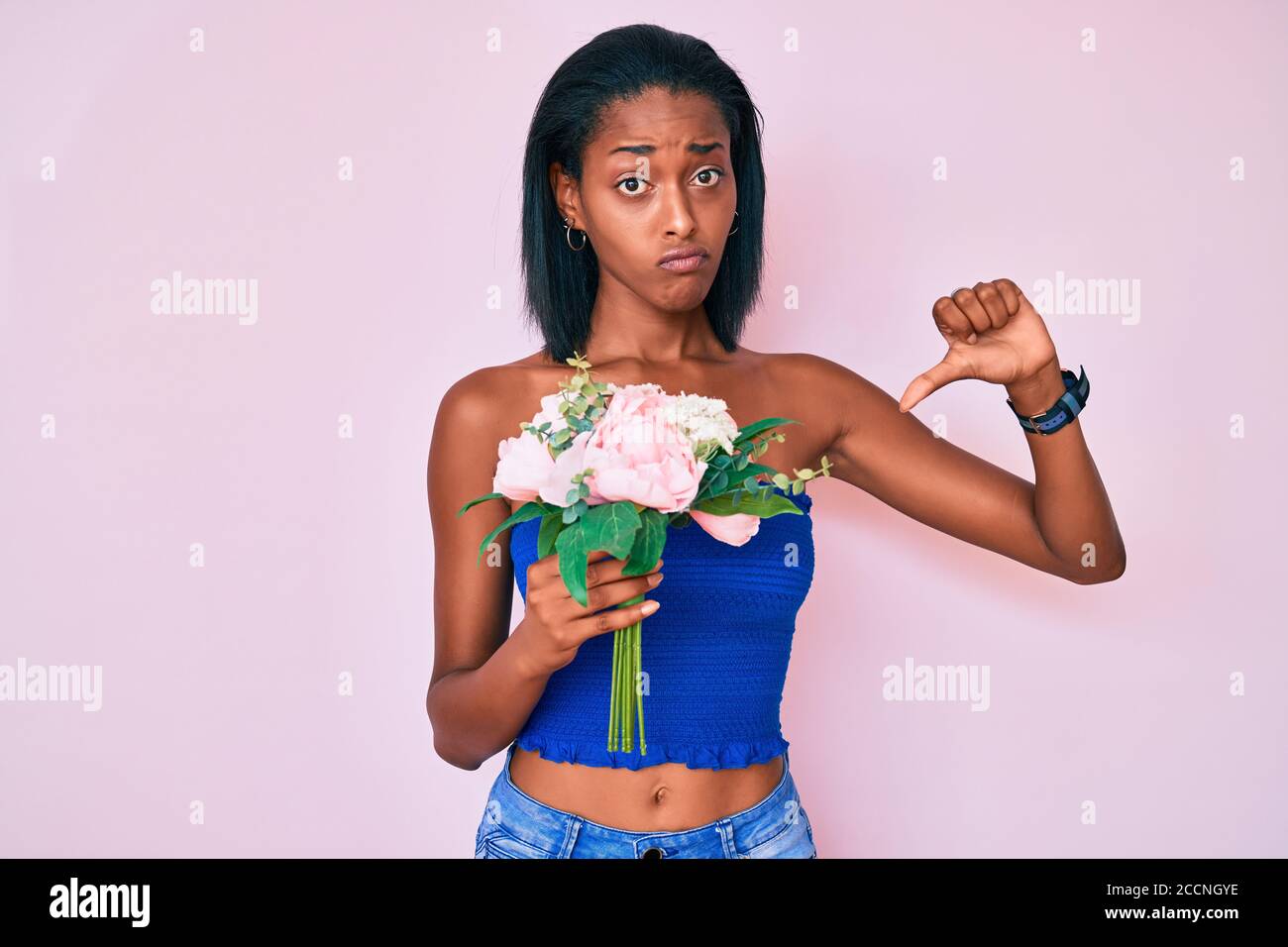 Young african american woman holding flowers with angry face, negative ...