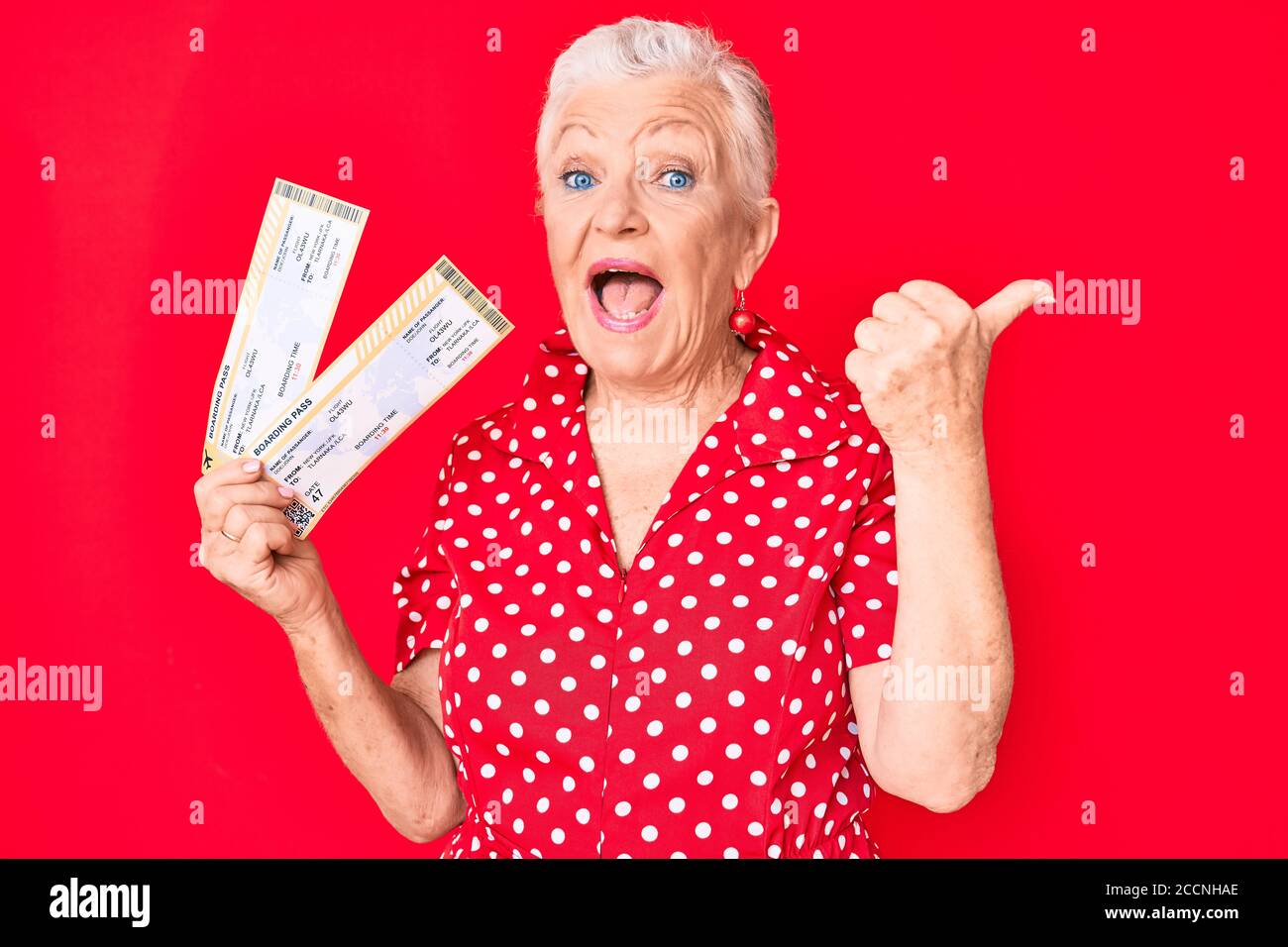 Senior beautiful woman with blue eyes and grey hair holding boarding ...