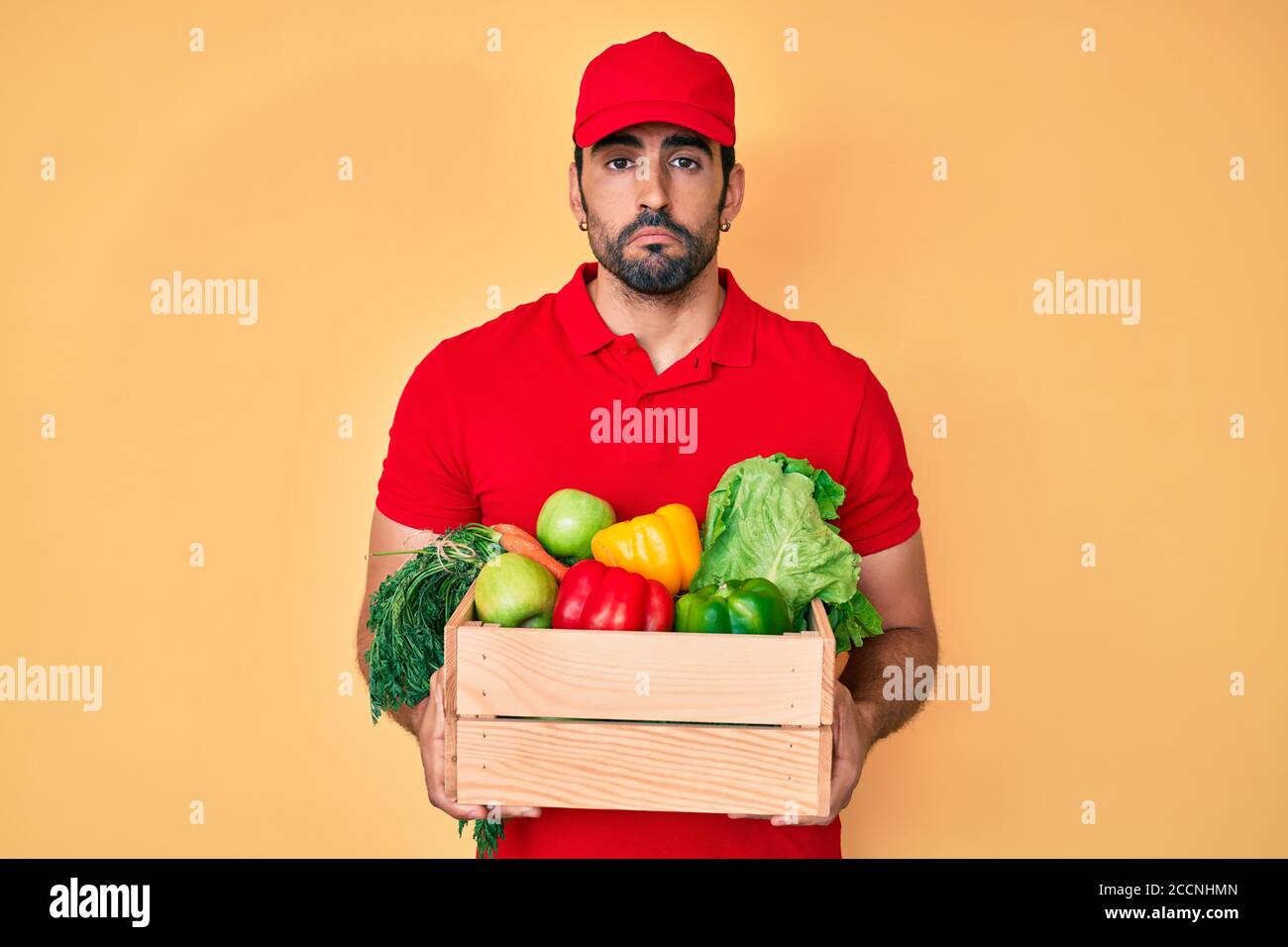 Handsome hispanic man with beard wearing uniform holding delivery food ...