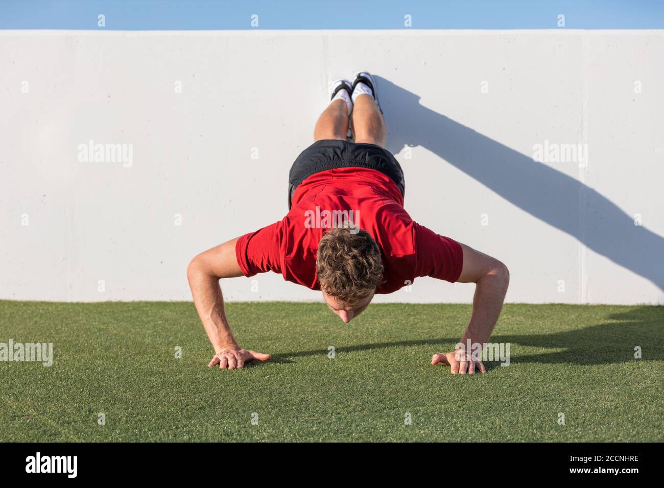 Push up fitness man training using wall doing decline pushup at outdoor ...