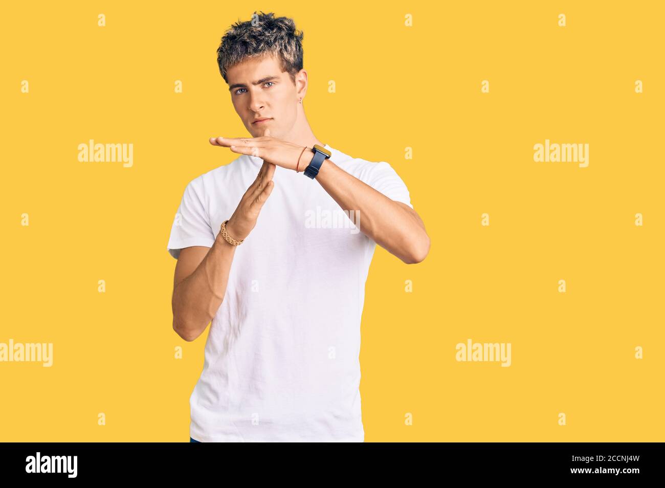 Young handsome man wearing casual white tshirt doing time out gesture ...
