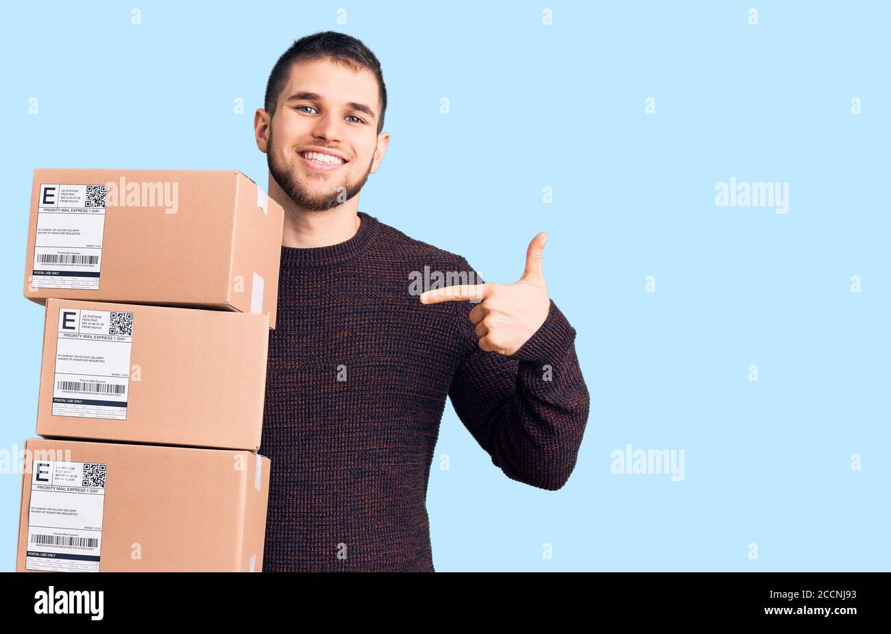 Young handsome man holding delivery package pointing finger to one self ...