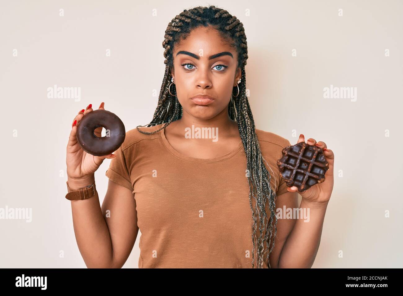 Young african american woman with braids holding chocolate donut and ...