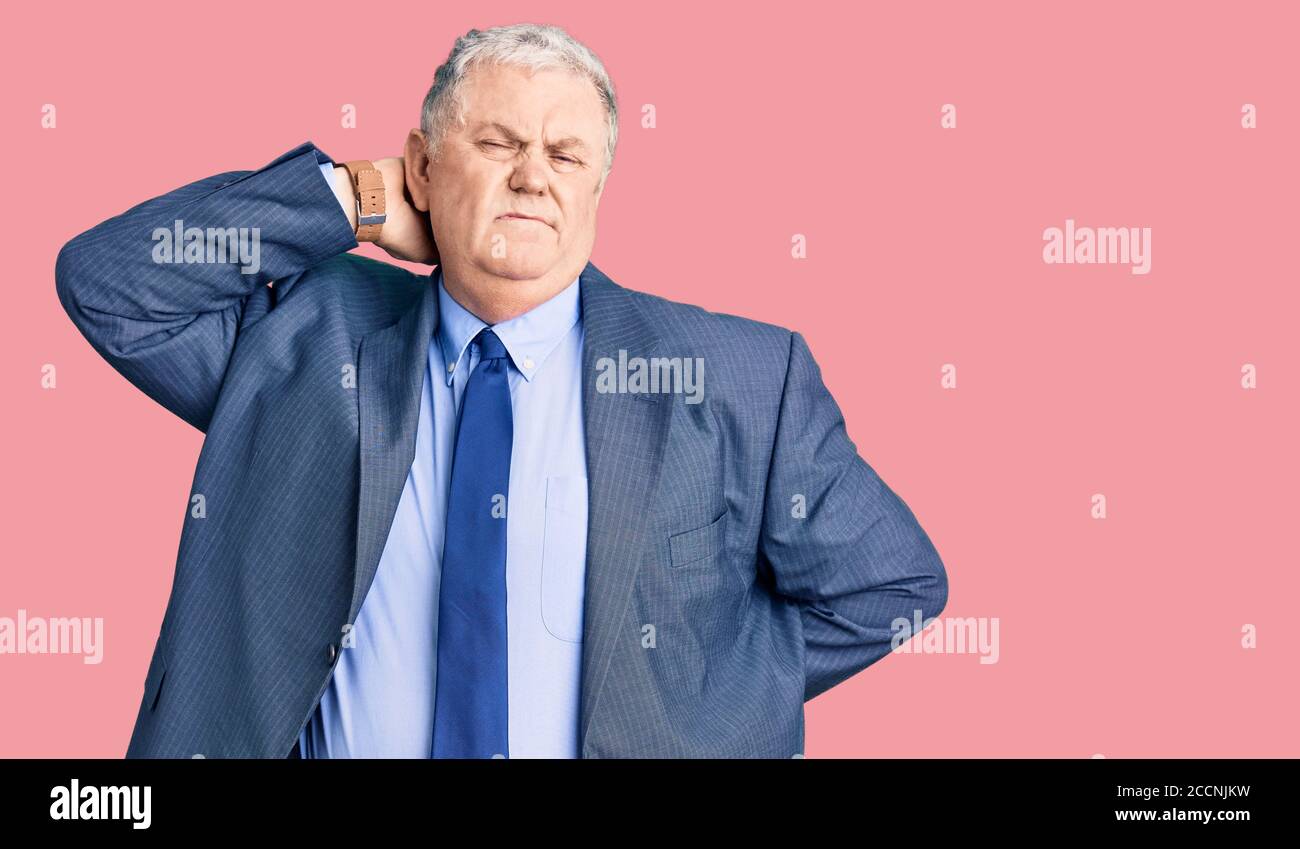Senior grey-haired man wearing business jacket suffering of neck ache ...