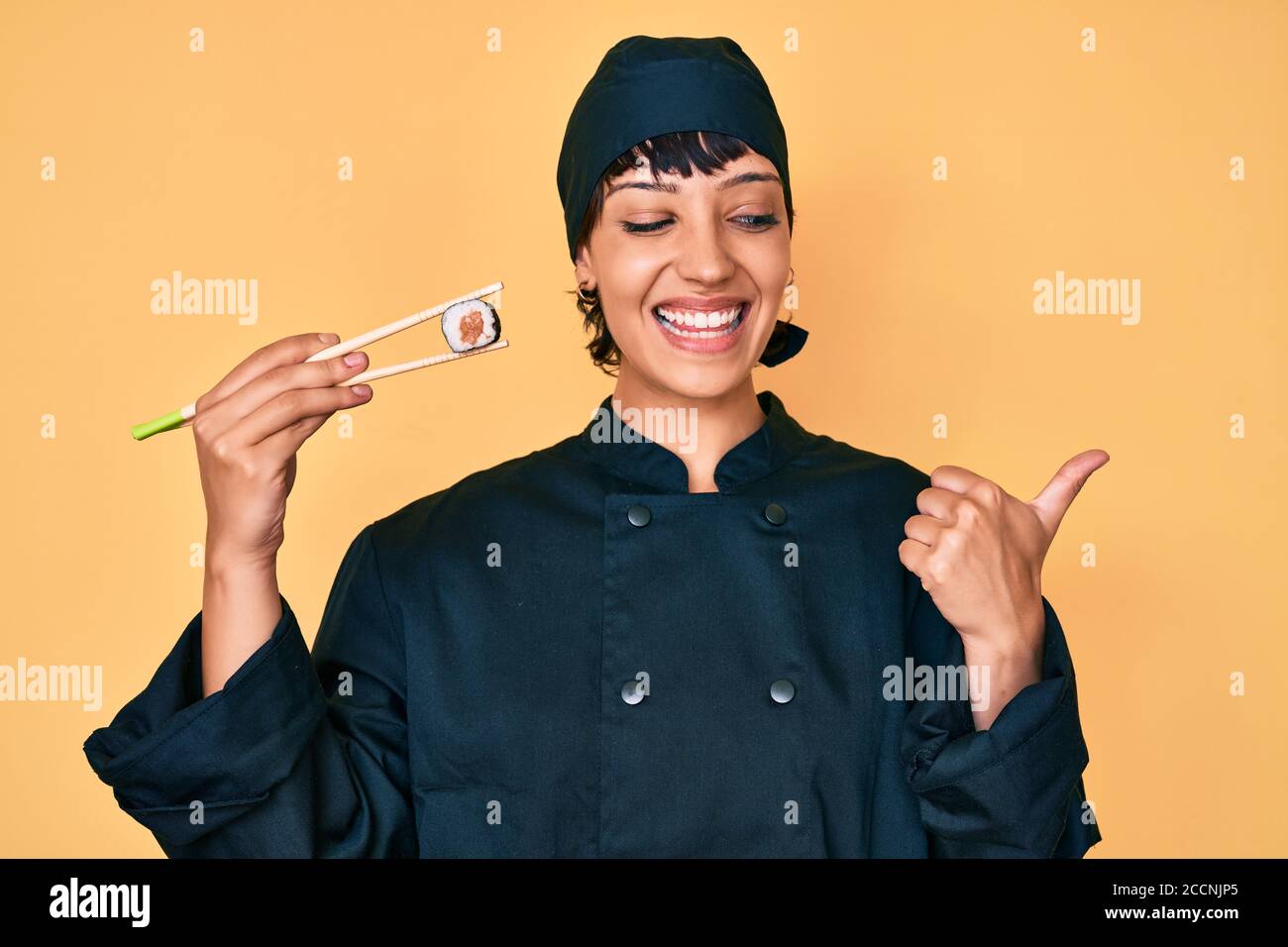 Beautiful brunettte woman chef holding sushi using chopsticks pointing ...