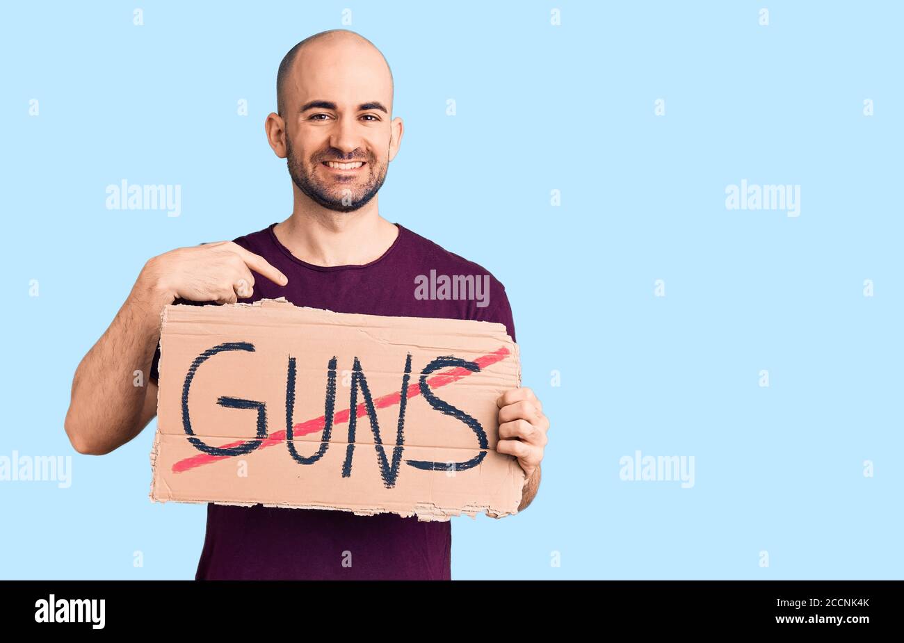 Young handsome man holding prohibited guns banner pointing finger to ...