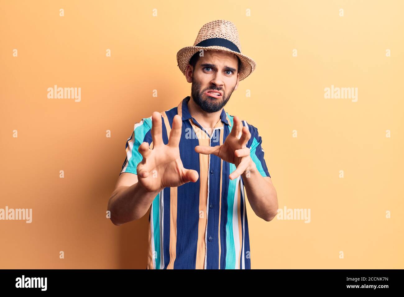 Young handsome man with beard wearing summer hat and shirt disgusted ...