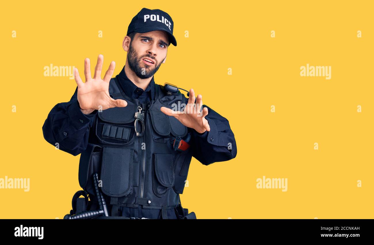 Young handsome man with beard wearing police uniform afraid and ...