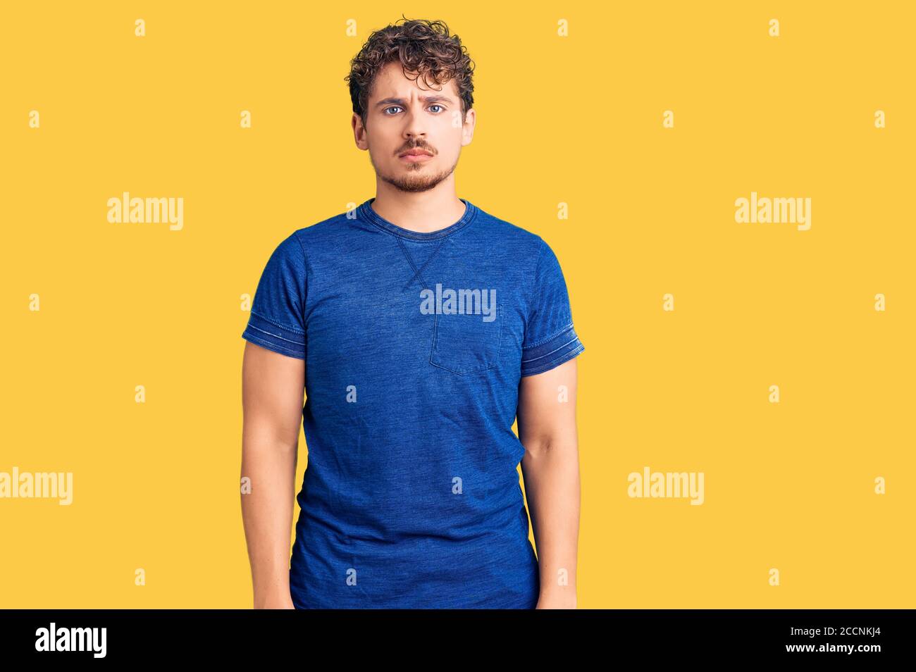 Young handsome man with curly hair wearing casual clothes depressed and ...