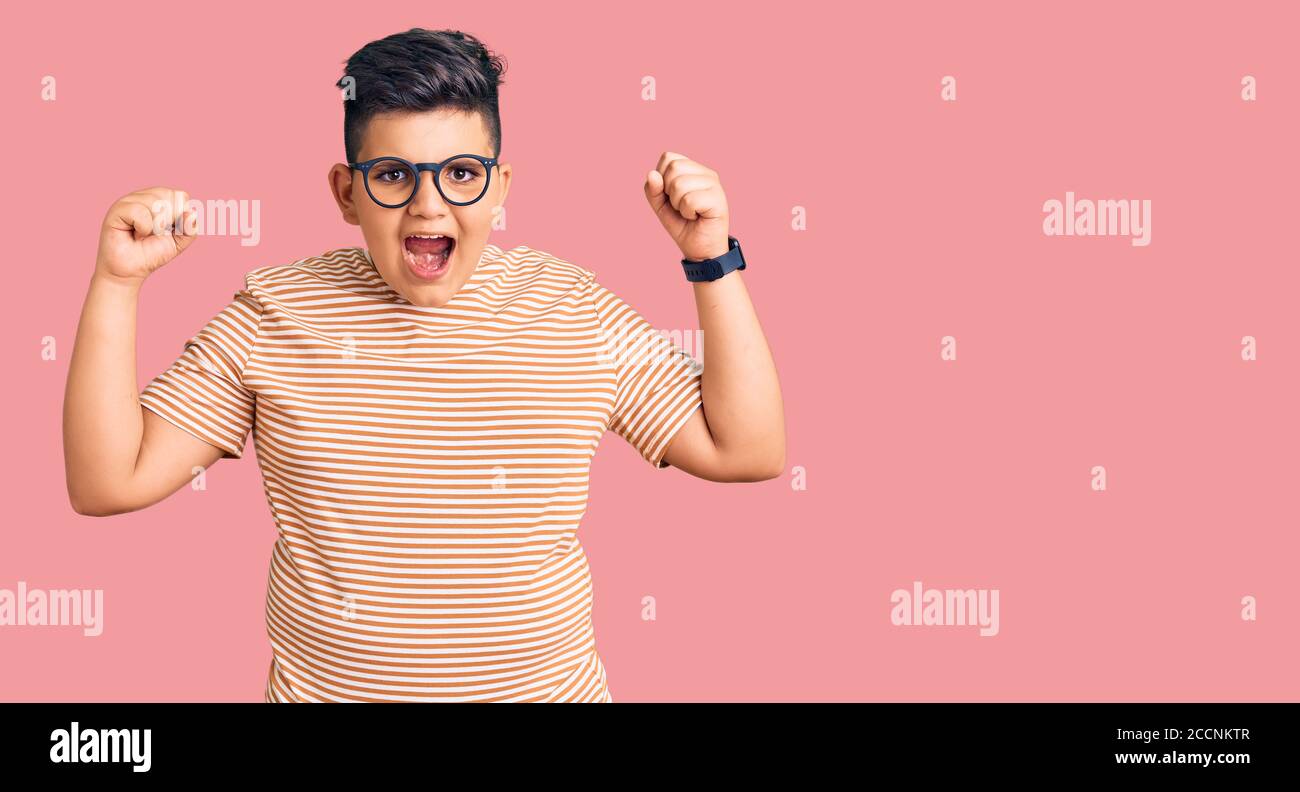 Little boy kid wearing casual clothes and glasses angry and mad raising ...