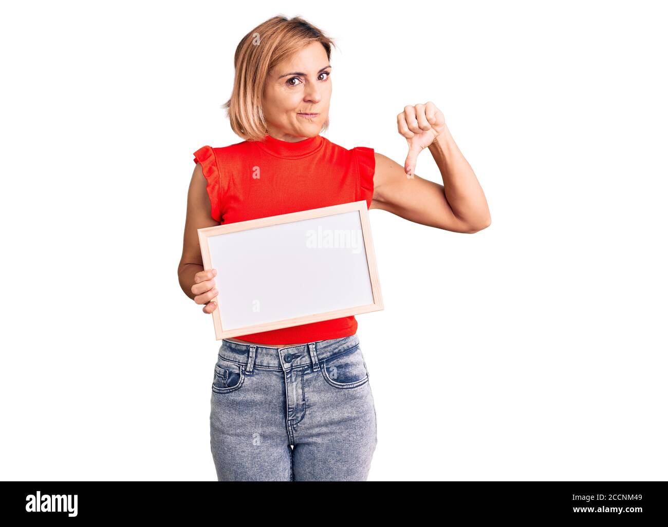 Young blonde woman holding empty white chalkboard with angry face ...