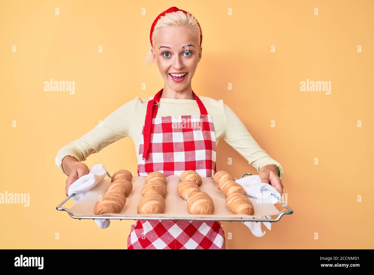 Young blonde woman wearing baker uniform holding homemade bread smiling ...