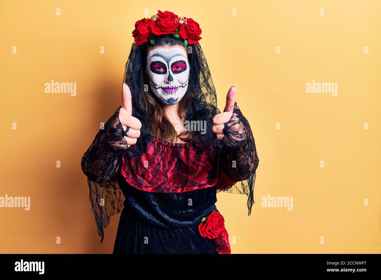 Young woman wearing day of the dead costume over yellow approving doing ...