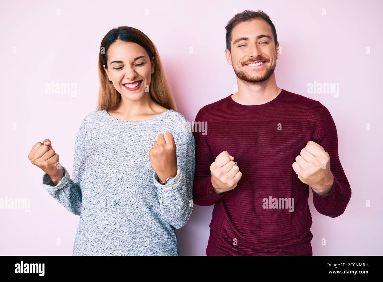 Beautiful couple wearing casual clothes excited for success with arms ...