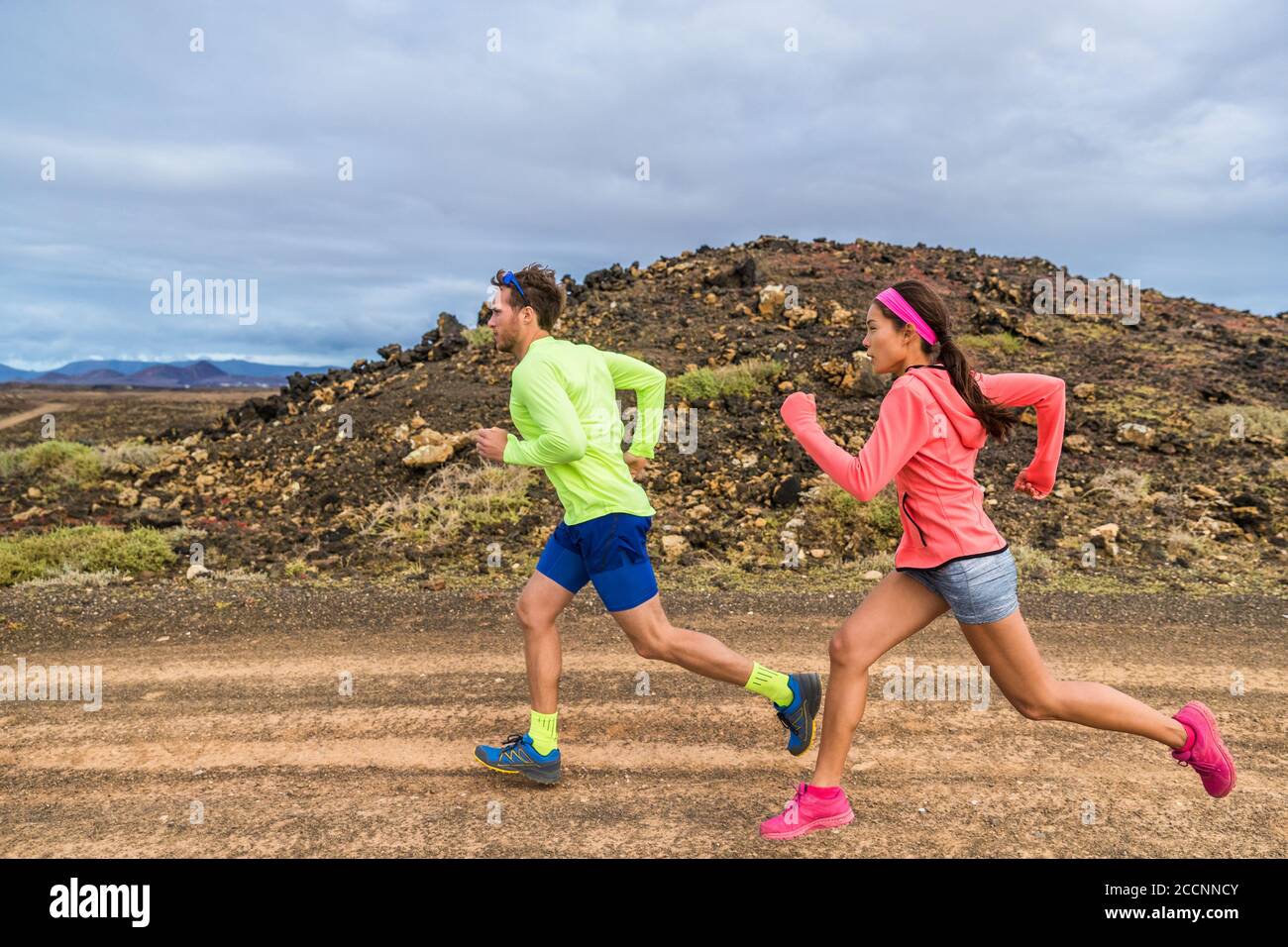 Trail run race ultra runners athletes couple running in rock path in ...