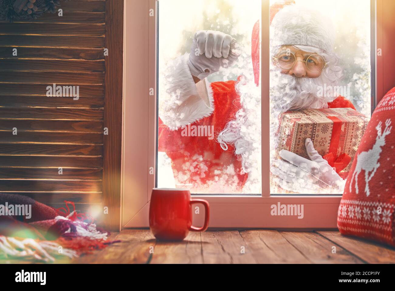 Merry Christmas! Santa Claus is knocking at window. Room decorated for ...