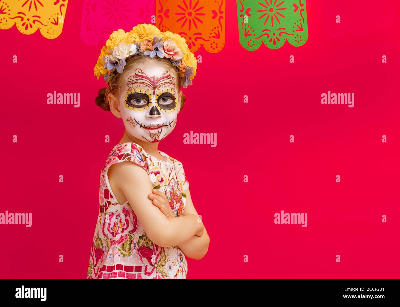 Adorable zombie in flower wreath posing on red background. Happy child ...