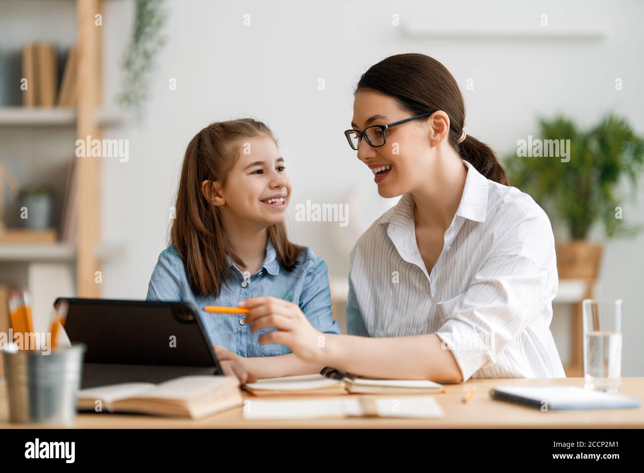 Back to school. Happy child and adult are sitting at desk. Girl doing ...