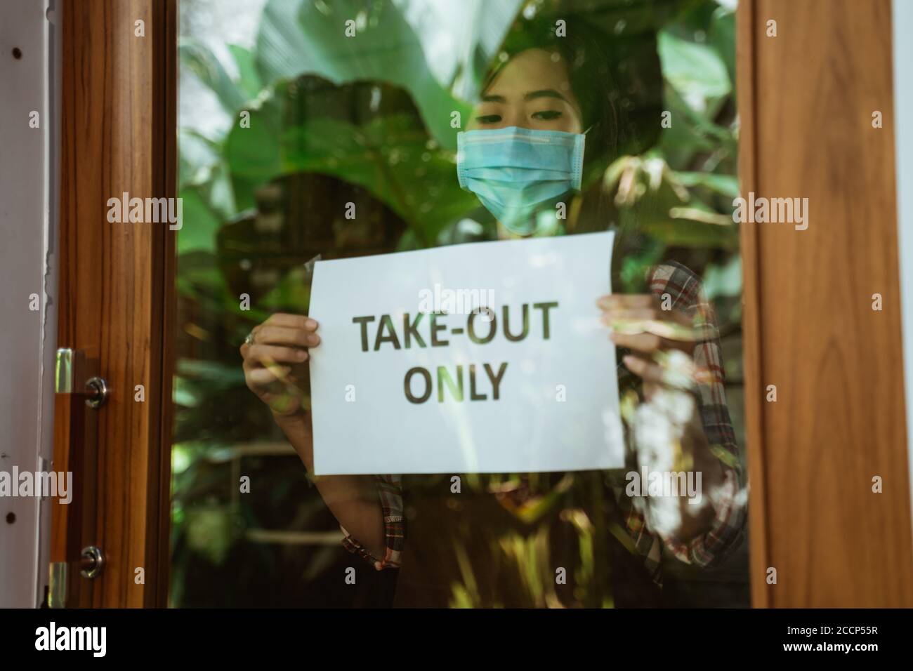 coffee shop owner sticking sign on the front door. take out only sign ...