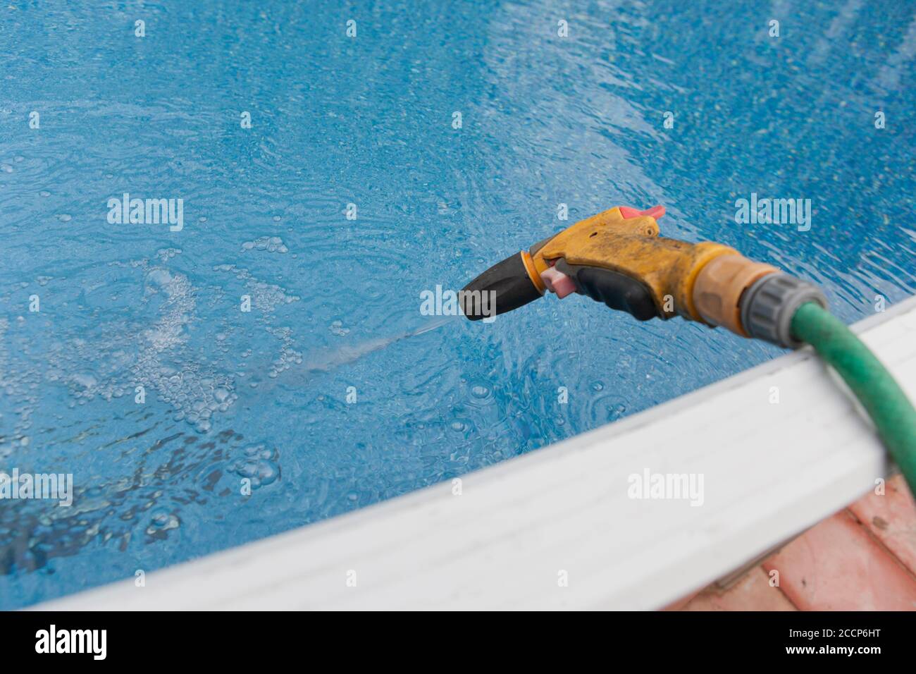Using a garden hose with pistol sprinkler to fiil outdoor pool with ...