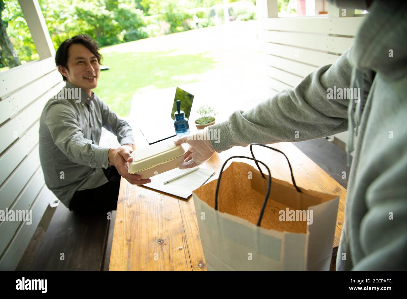 Mature Man Receiving Lunch Box from Delivery Person Stock Photo - Alamy