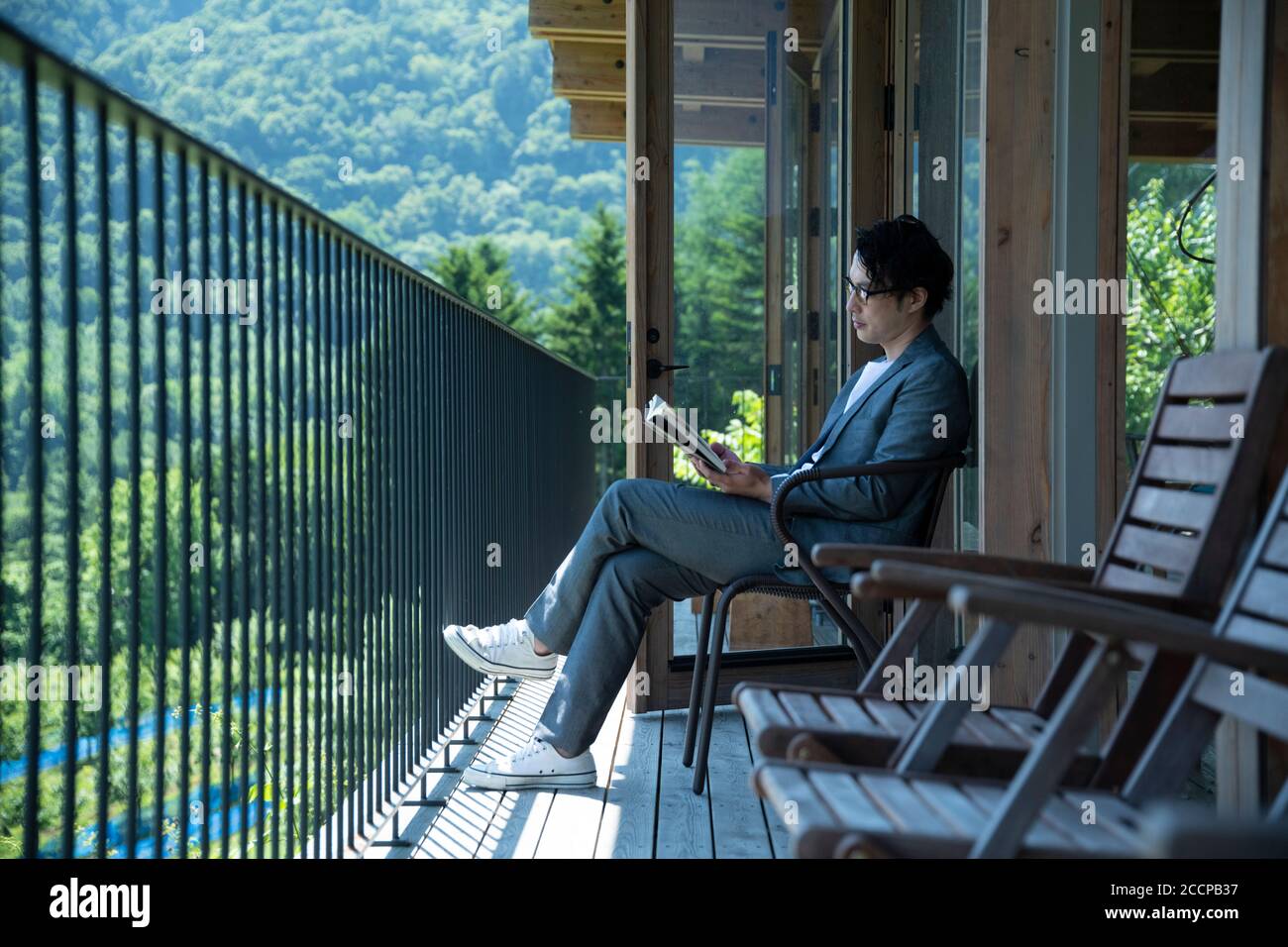 Businessman Reading a Book on the Balcony Stock Photo - Alamy