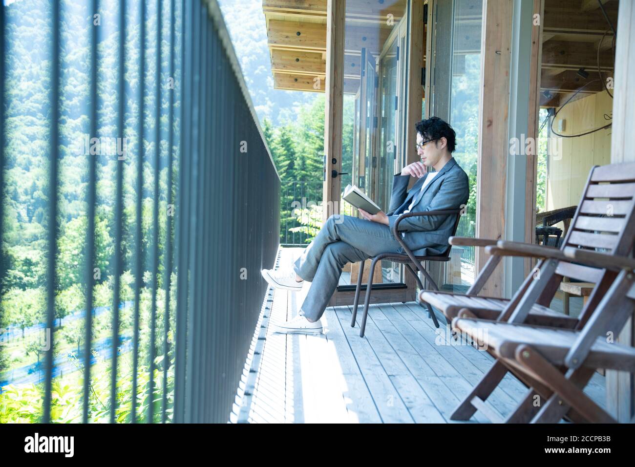 Businessman Reading a Book on the Balcony Stock Photo - Alamy