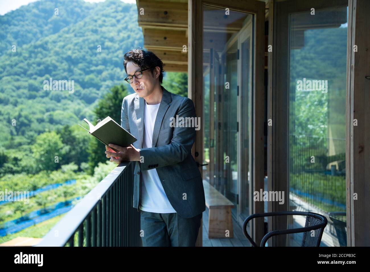 Businessman Reading a Book on the Balcony Stock Photo - Alamy