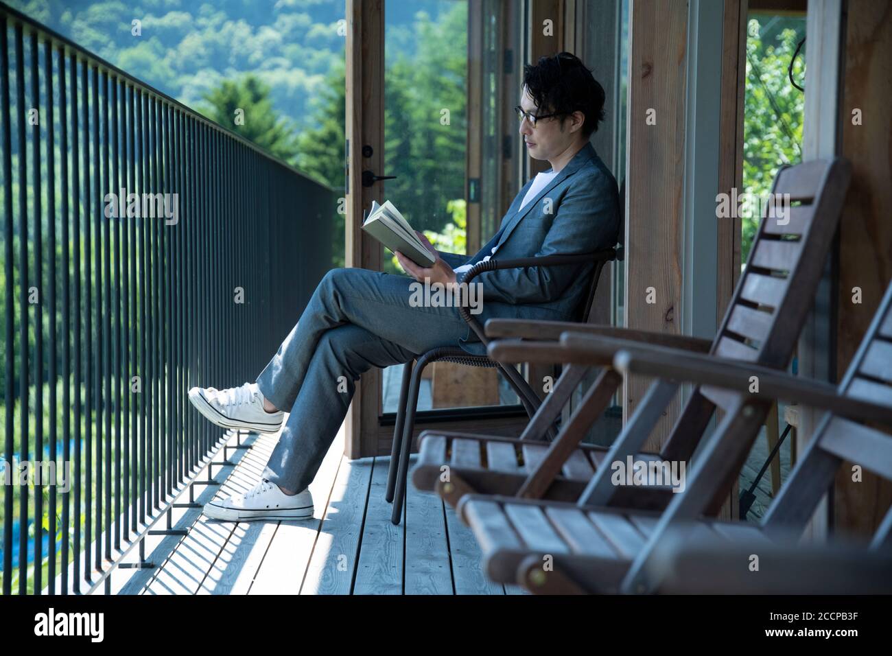 Businessman Reading a Book on the Balcony Stock Photo - Alamy