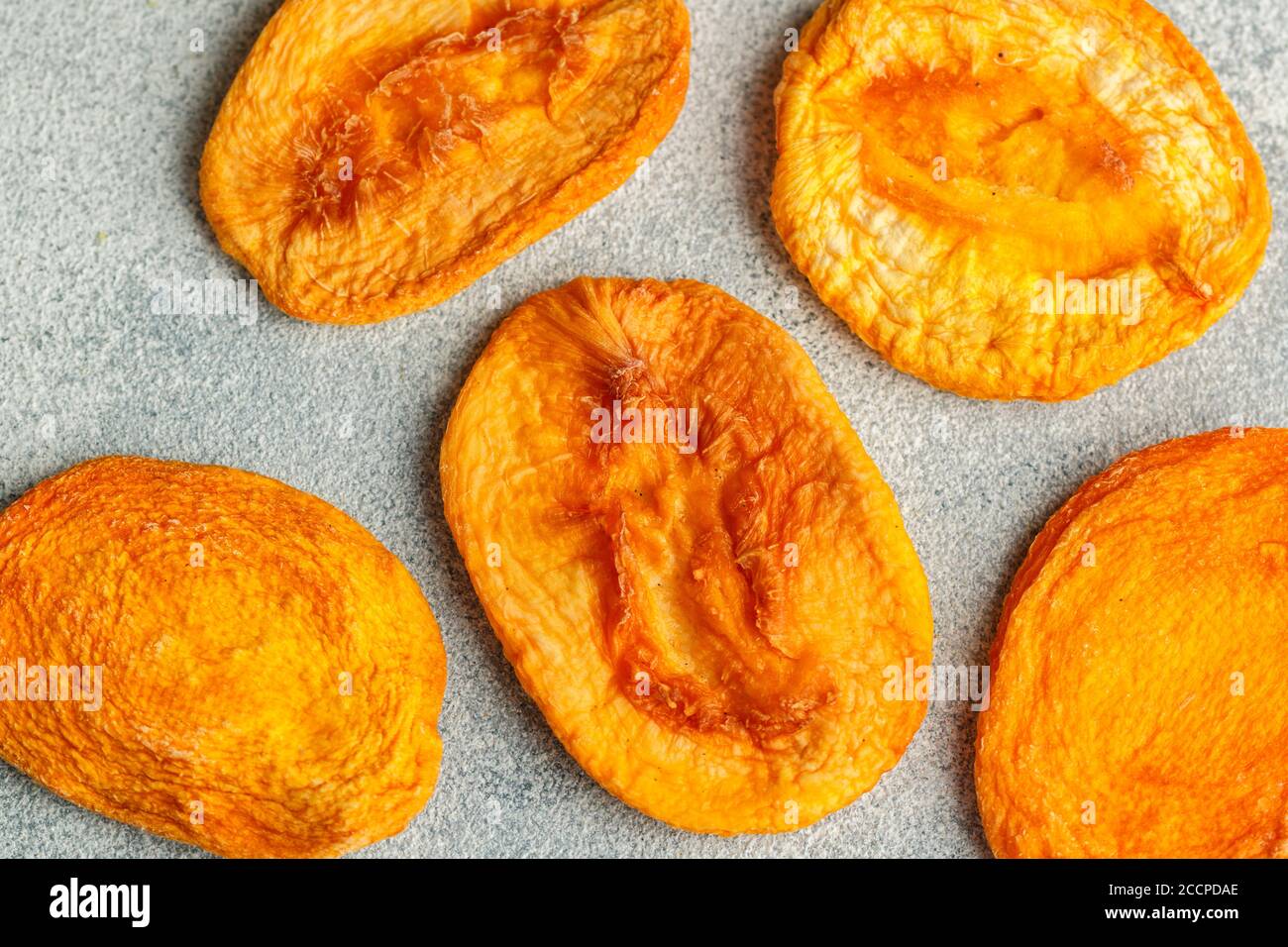 Dried delicious peaches on a gray concrete or stone background. An ...