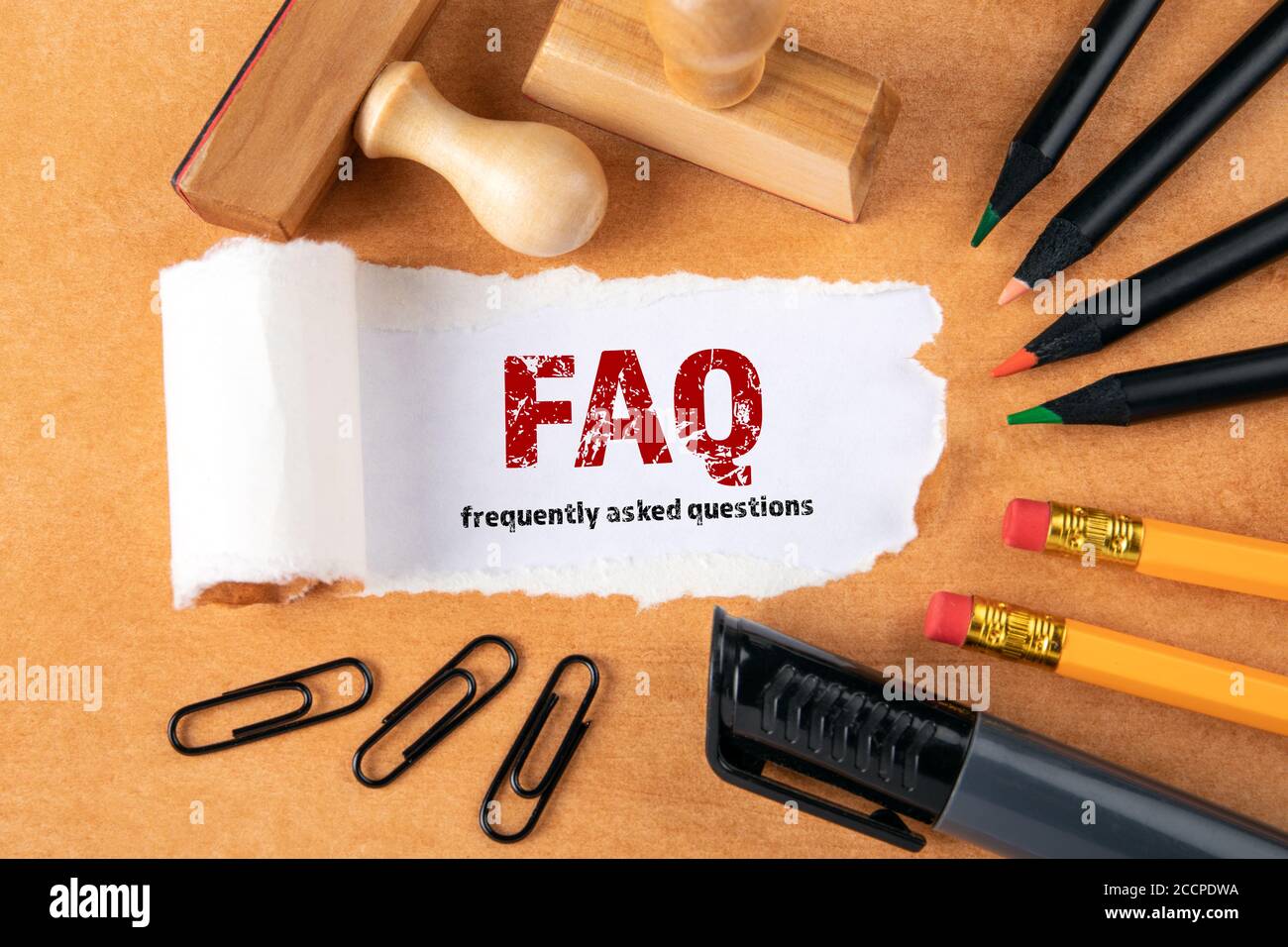 FAQ frequently asked questions concept. Text under torn paper. Pencils ...