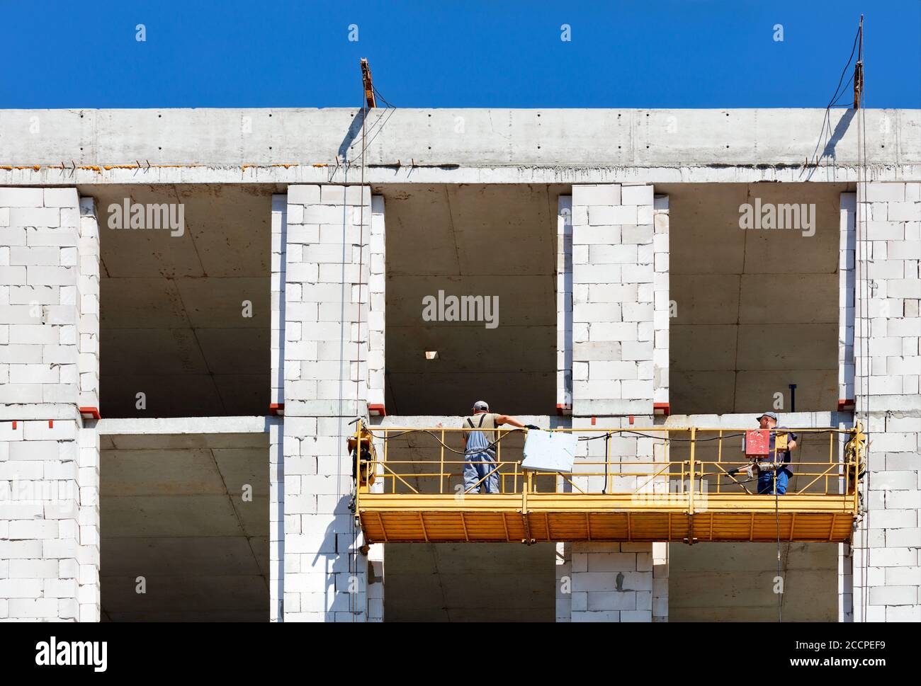 Construction cradle with workers on the wall of a house under ...